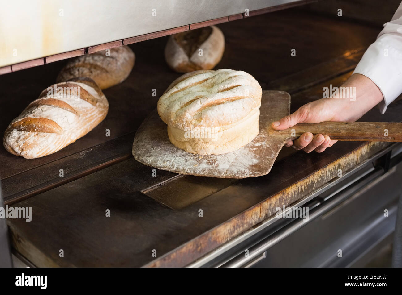 Happy baker taking out fresh loaf Stock Photo - Alamy