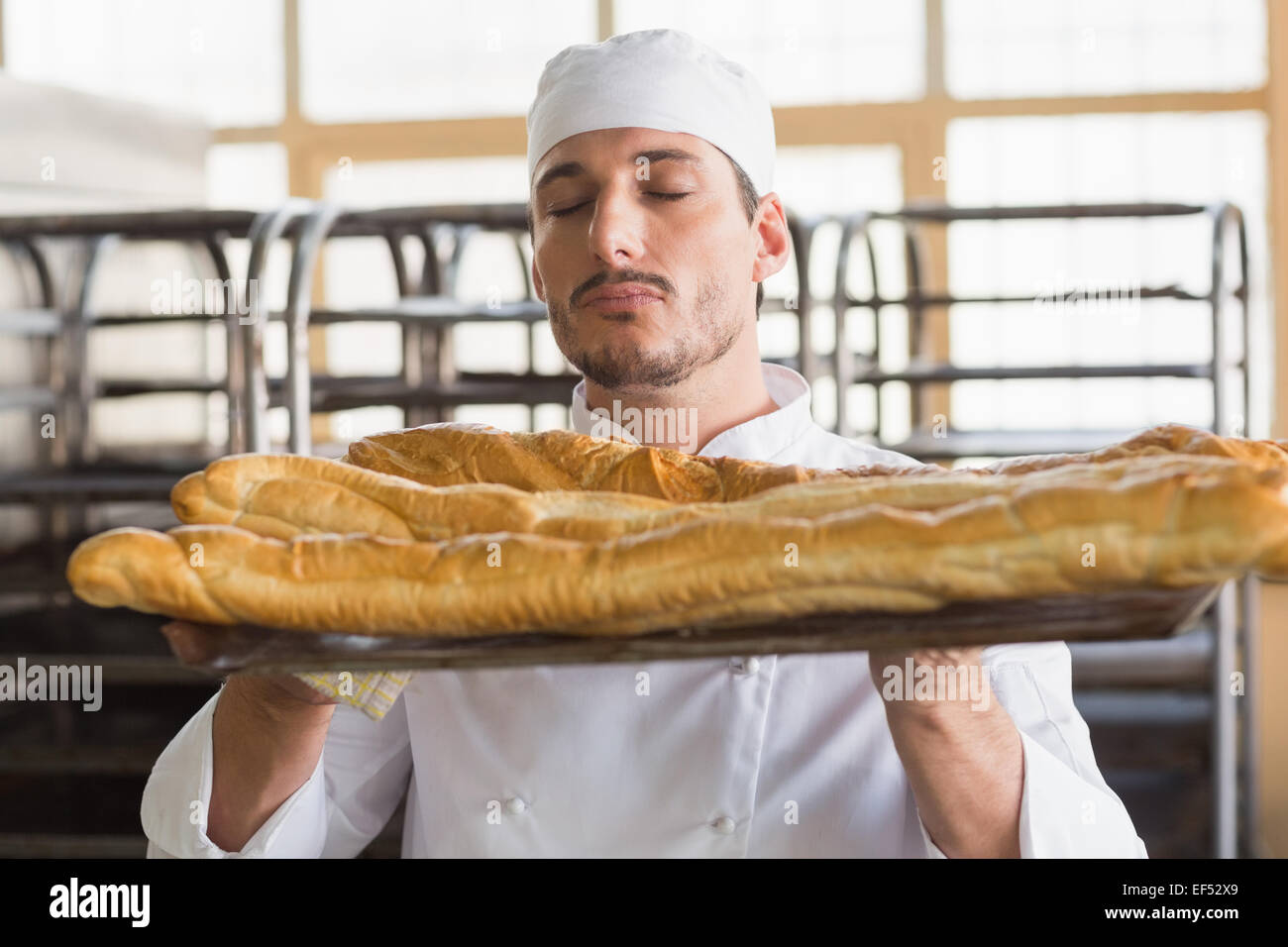 Baker smelling freshly baked baguettes Stock Photo - Alamy