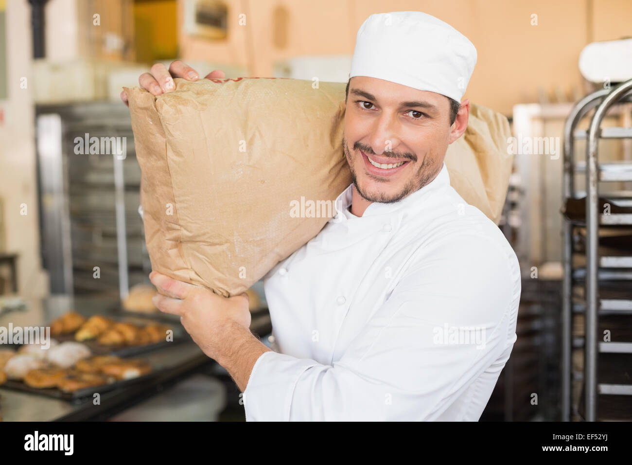 Smiling baker holding bag of flour Stock Photo - Alamy