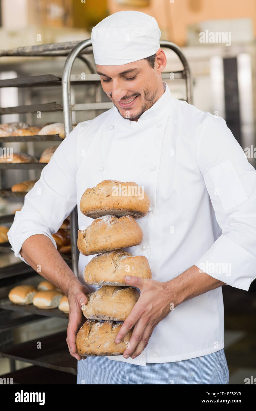 Smiling baker holding fresh loaves Stock Photo - Alamy