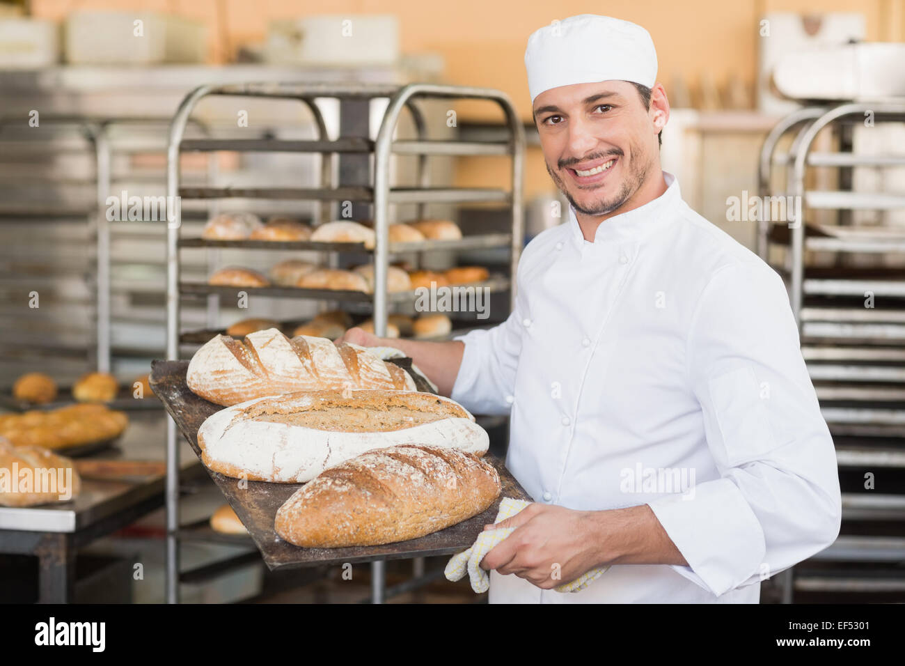 Smiling baker holding tray of bread Stock Photo - Alamy