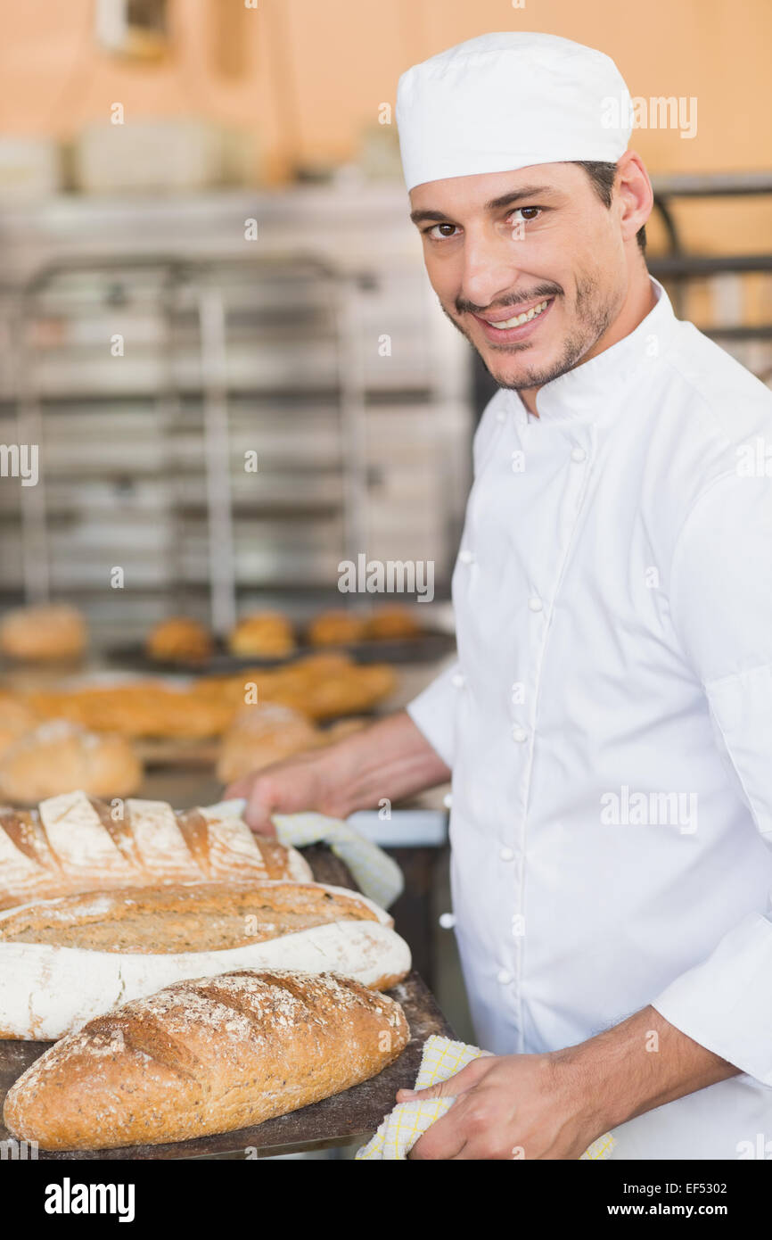 Smiling baker holding tray of bread Stock Photo - Alamy