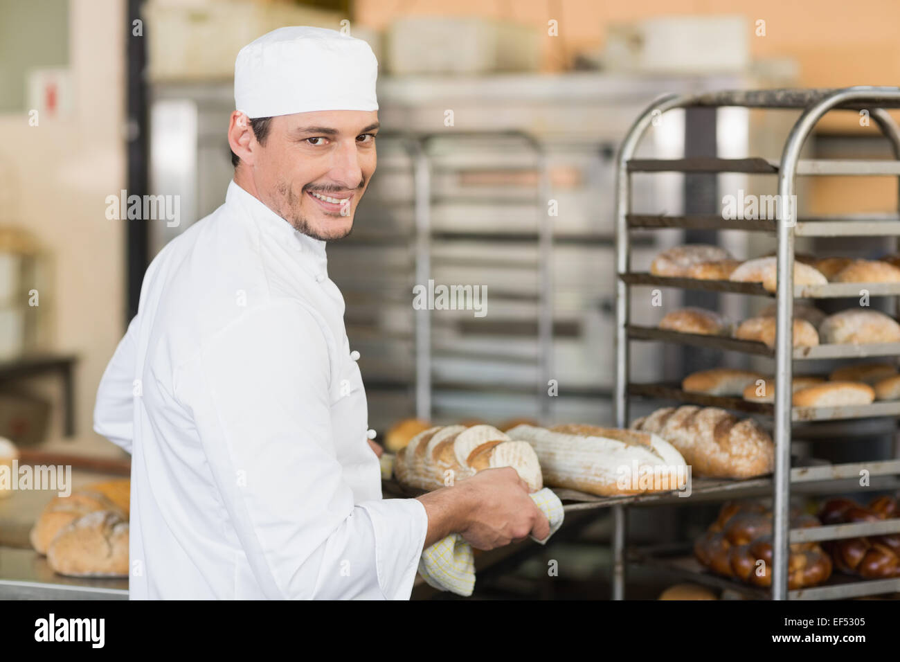 Smiling baker holding tray of bread Stock Photo - Alamy