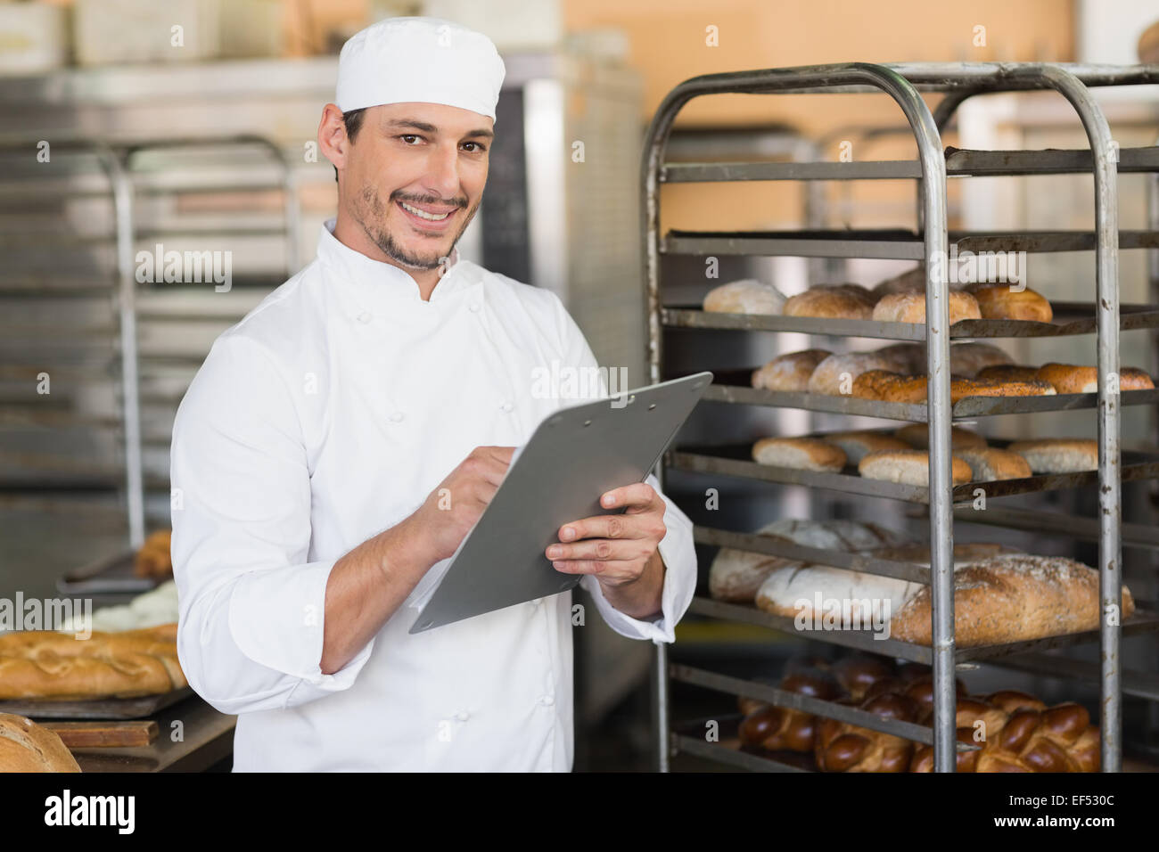 Smiling baker writing on clipboard Stock Photo - Alamy