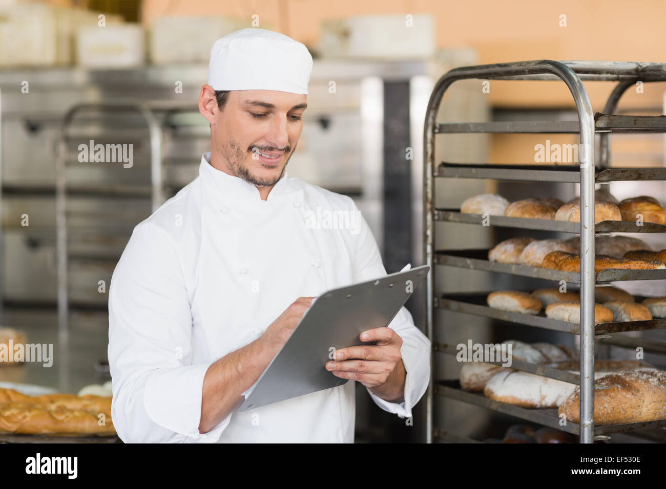 Smiling baker writing on clipboard Stock Photo - Alamy
