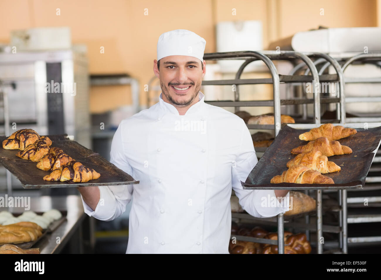 Smiling baker holding trays of croissants Stock Photo - Alamy