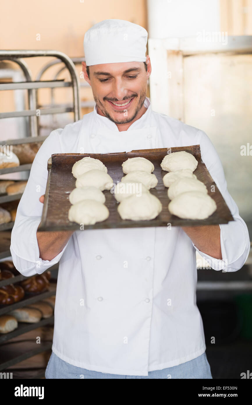 Smiling baker holding tray of raw dough Stock Photo - Alamy