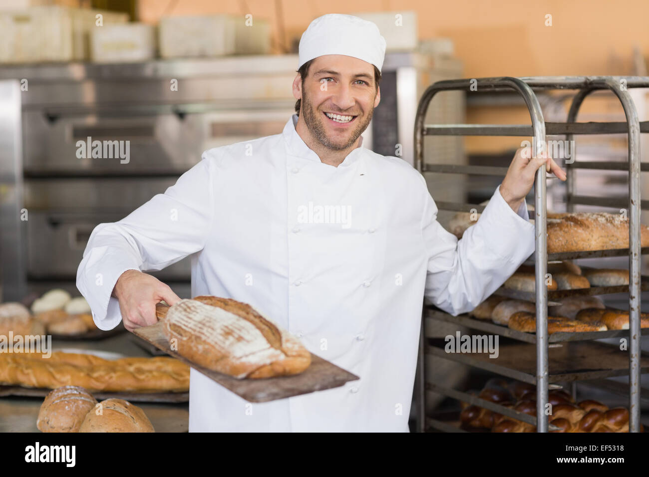 Smiling baker looking at camera holding bread Stock Photo - Alamy