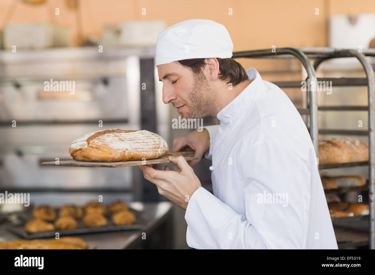 Smiling baker smelling fresh bread Stock Photo - Alamy