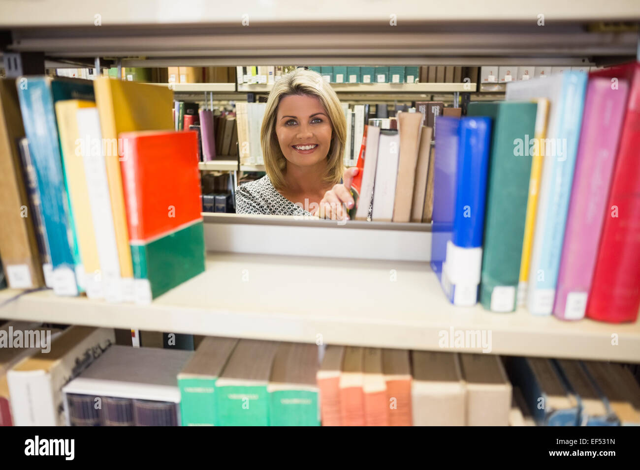 Mature student taking a book in library Stock Photo - Alamy