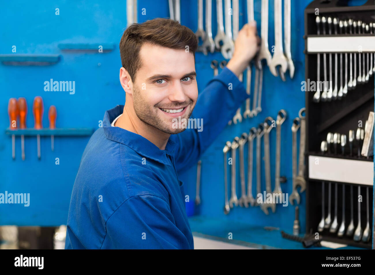 Mechanic taking a tool from wall Stock Photo - Alamy