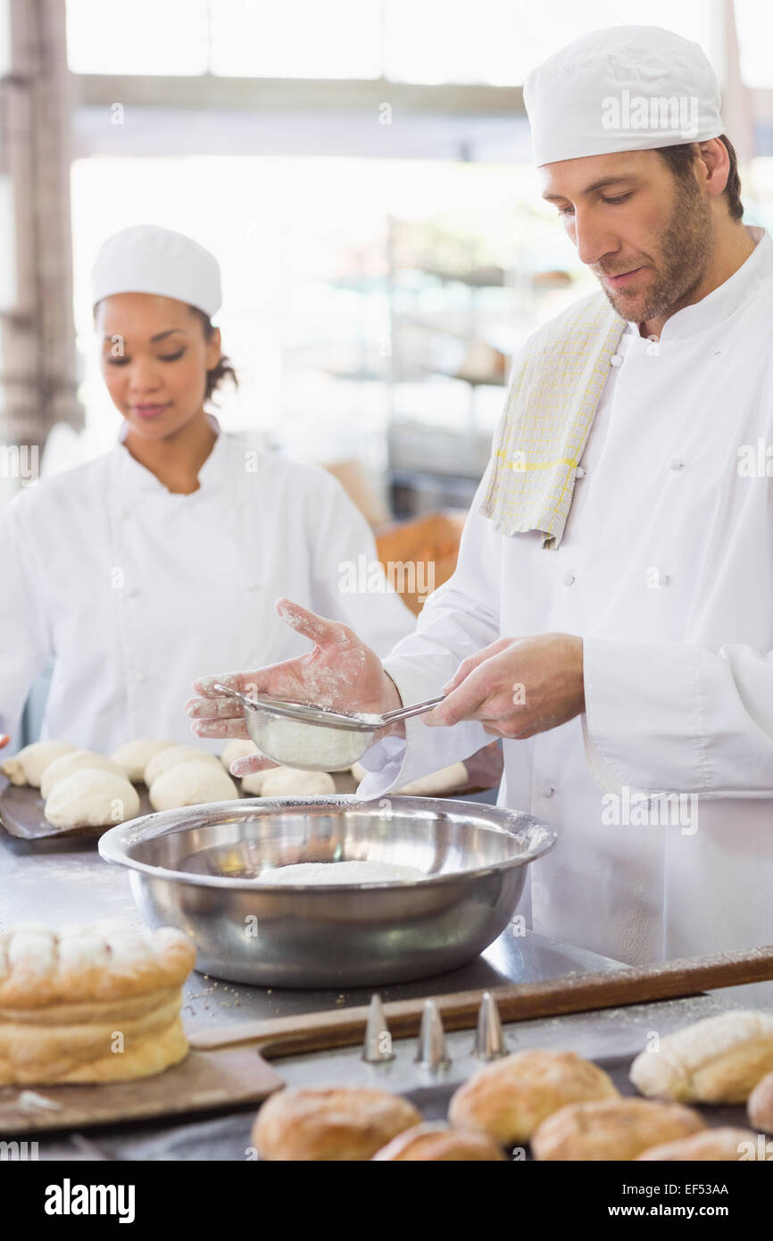 Baker sieving flour into a bowl Stock Photo - Alamy
