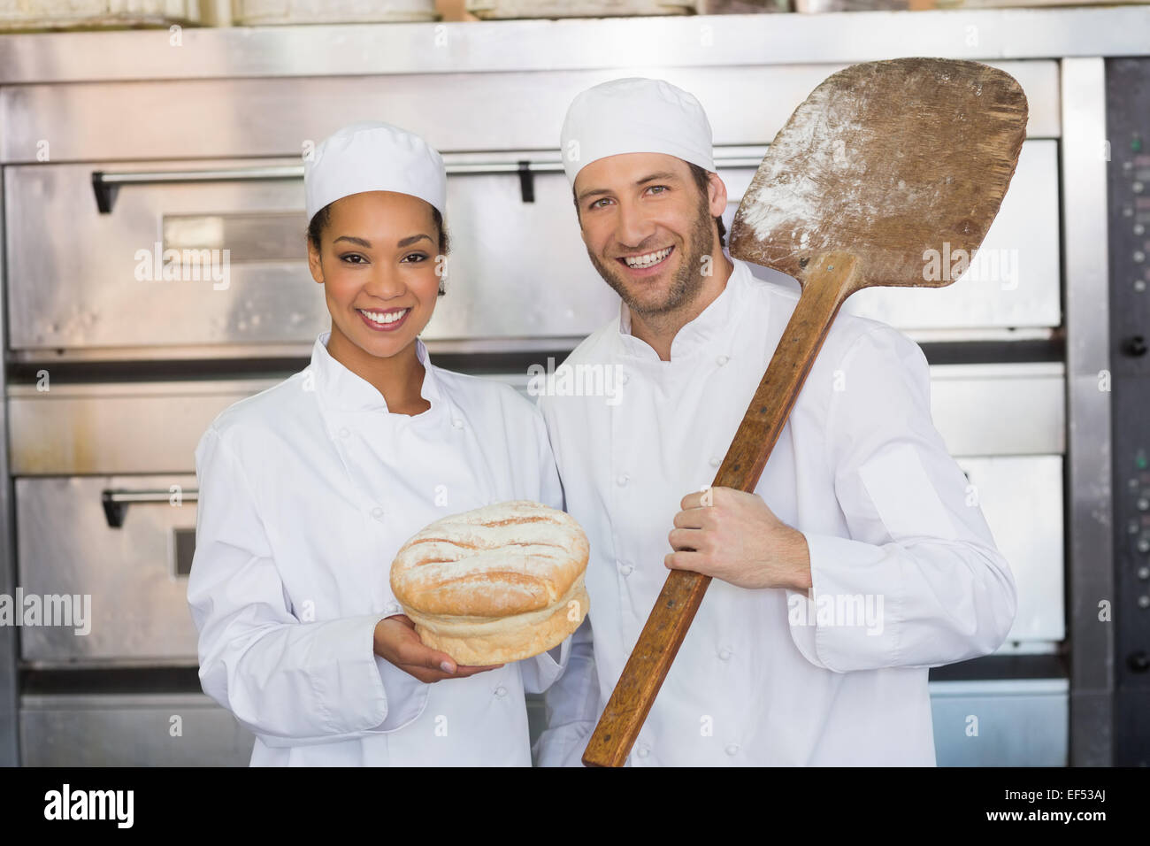 Team of bakers smiling at camera with loaf Stock Photo - Alamy