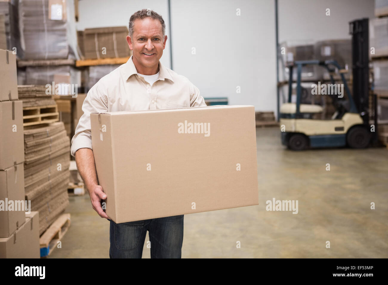 Smiling worker carrying a box Stock Photo - Alamy