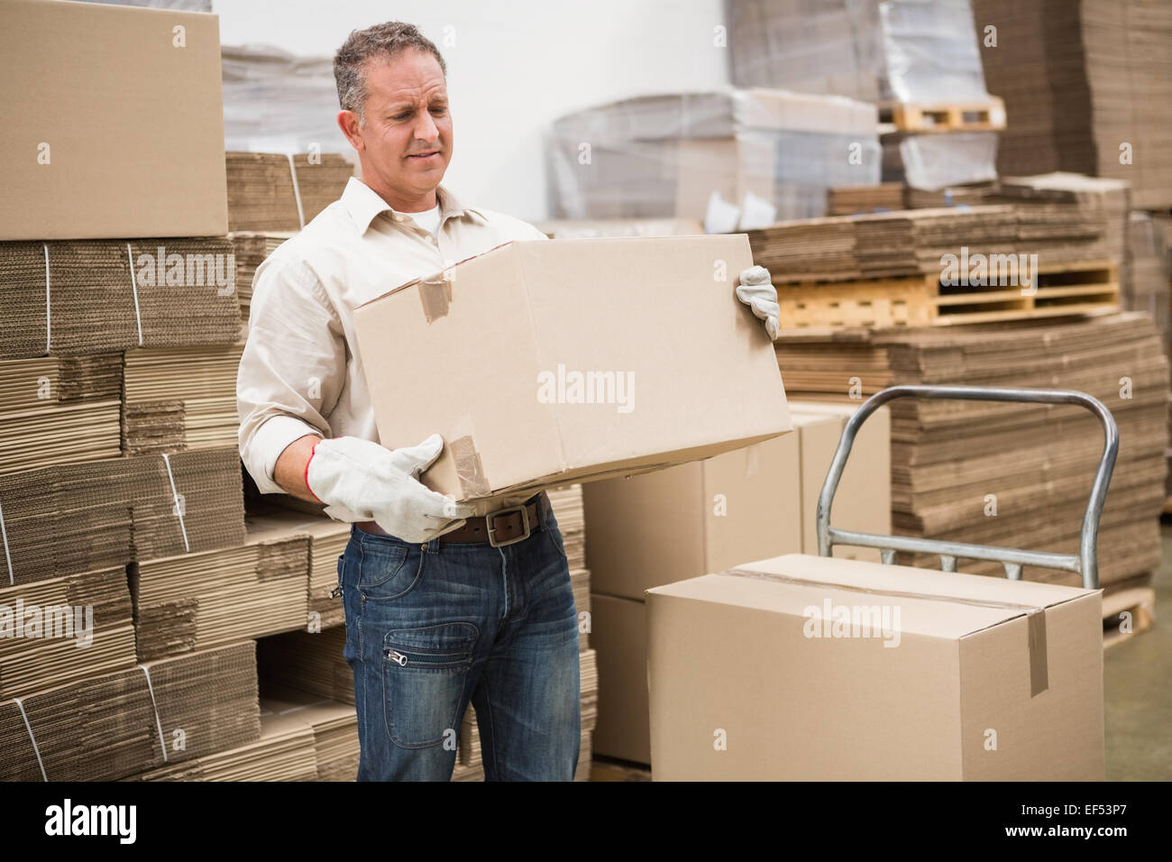 Worker carrying box in warehouse Stock Photo - Alamy