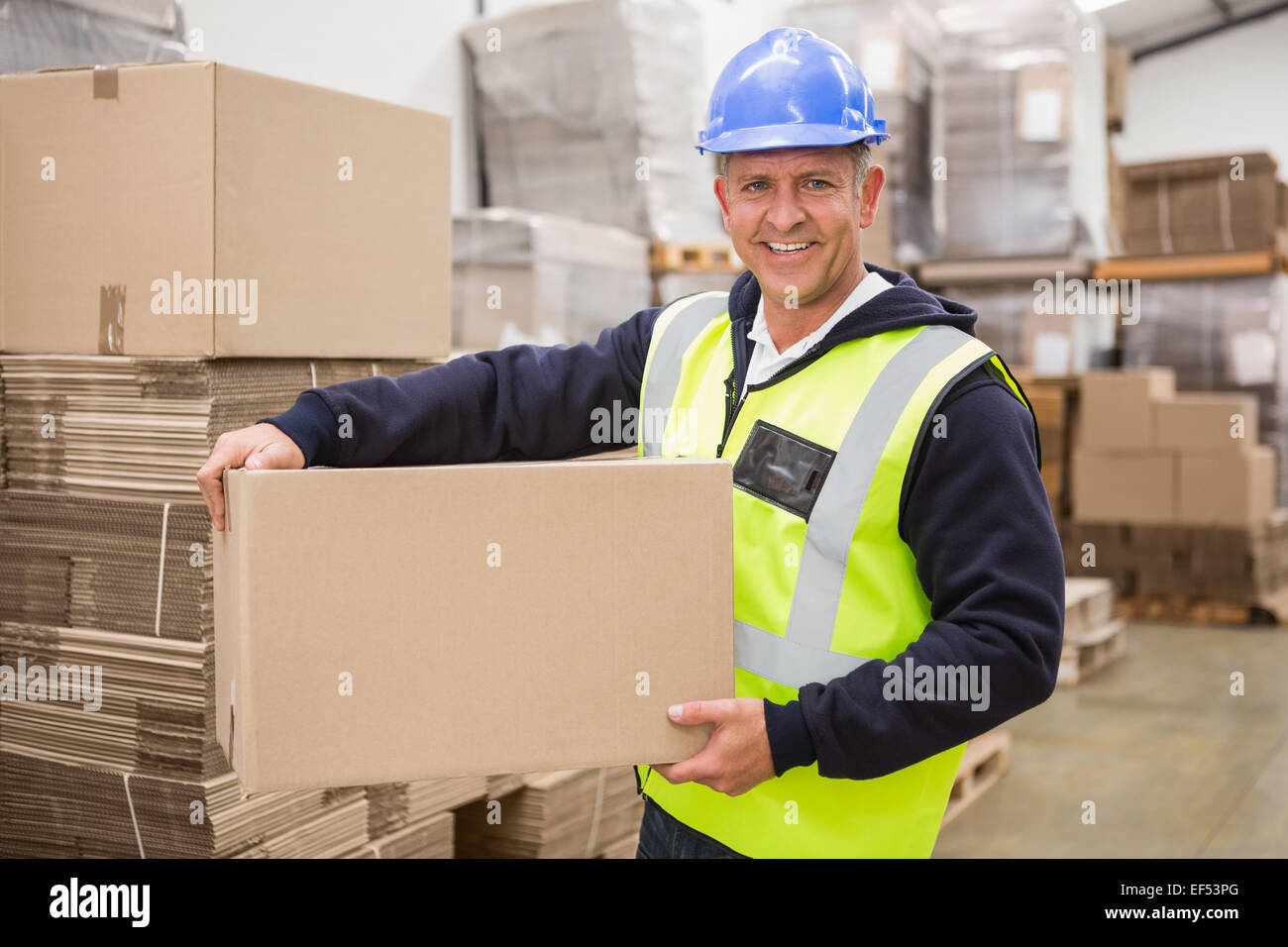 Worker carrying box in warehouse Stock Photo - Alamy