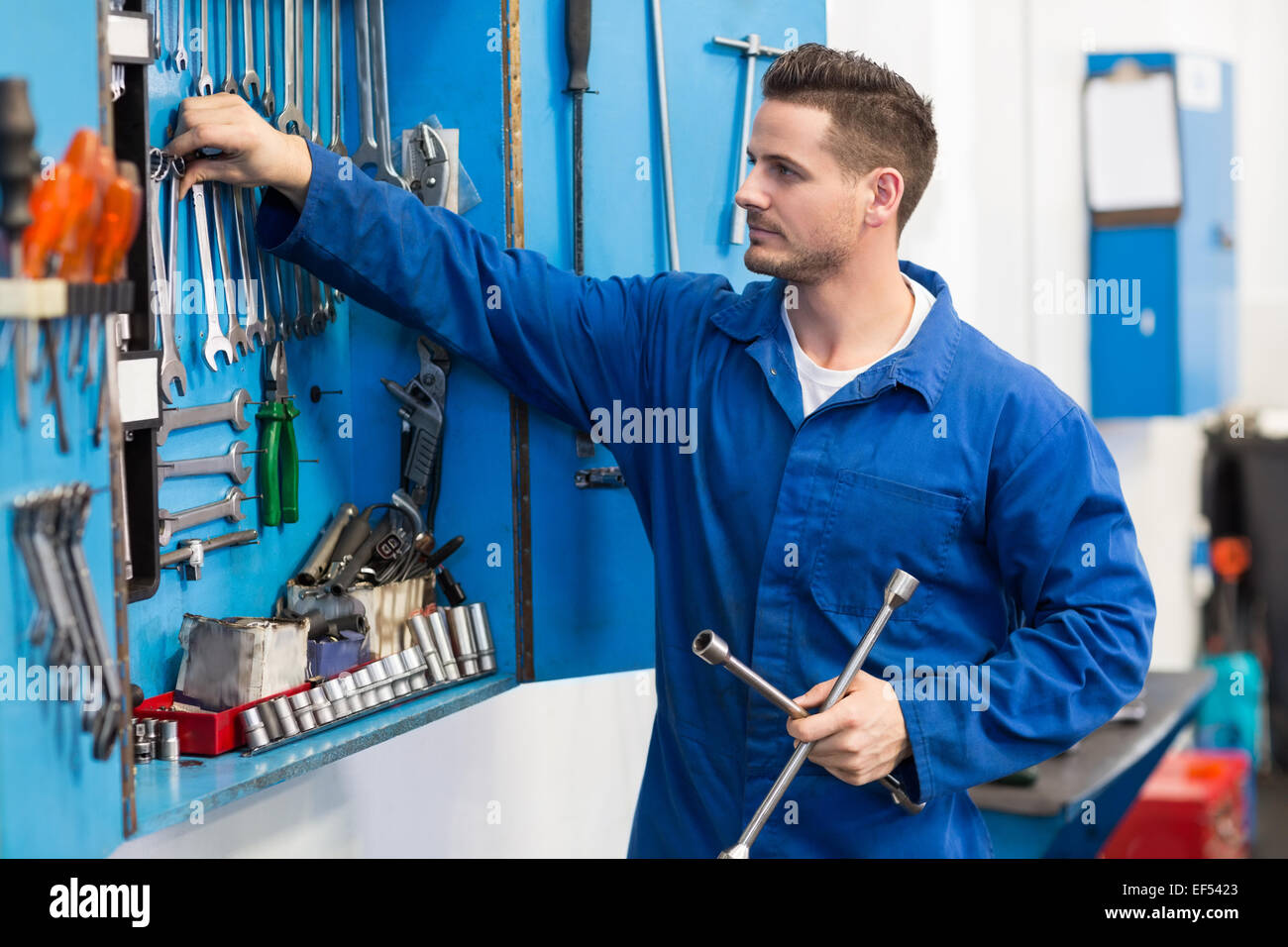 Mechanic taking a tool from wall Stock Photo - Alamy