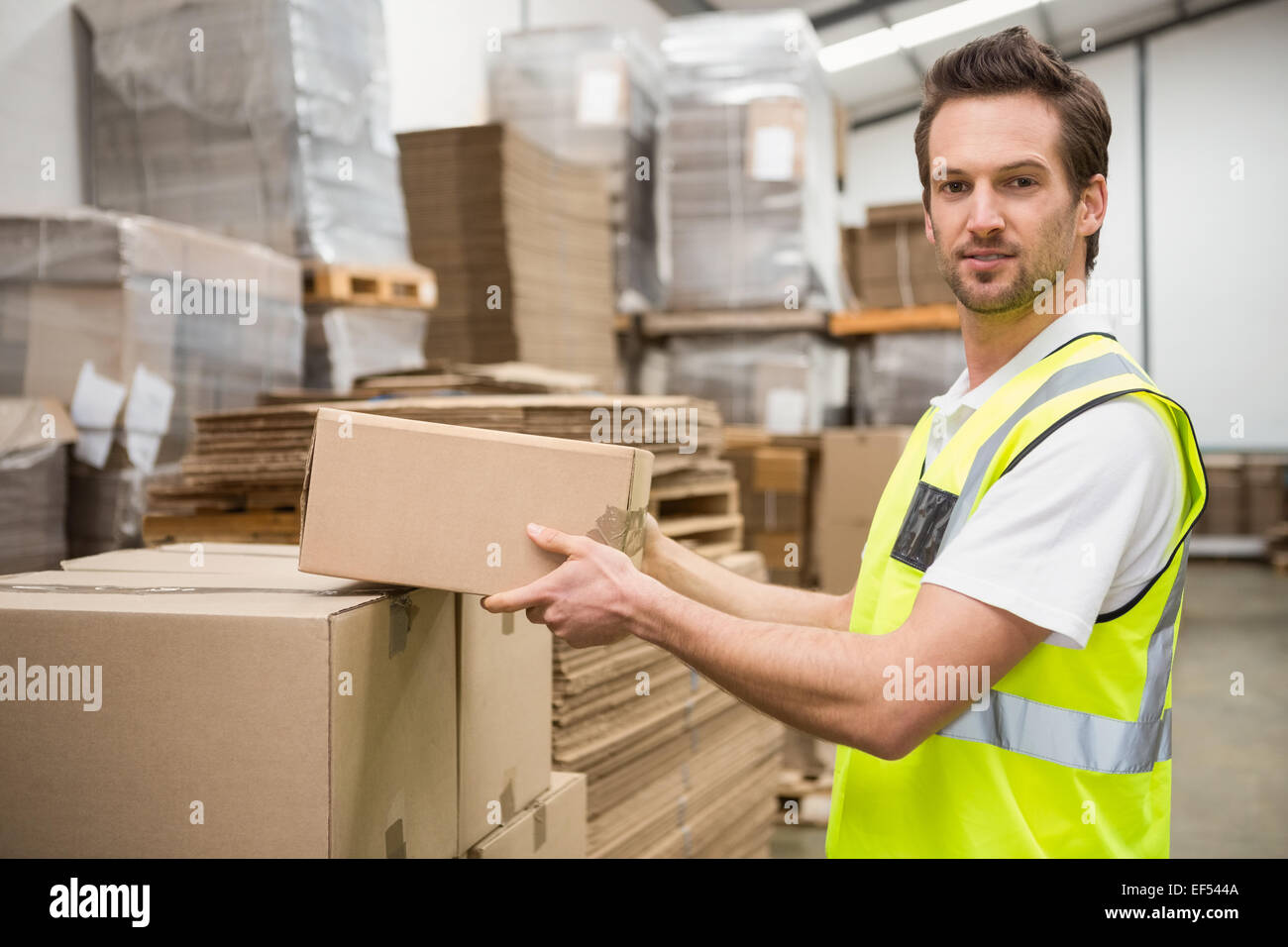 Smiling warehouse worker taking a box Stock Photo - Alamy