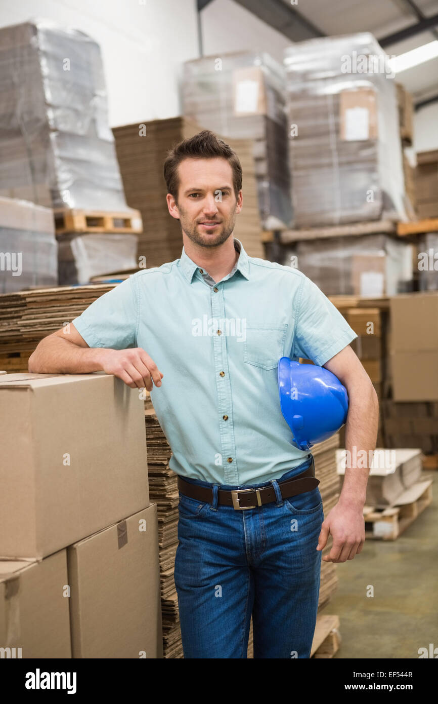 Smiling warehouse worker leaning against boxes Stock Photo - Alamy