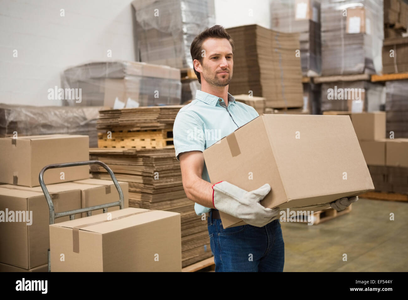 Worker carrying box in warehouse Stock Photo - Alamy