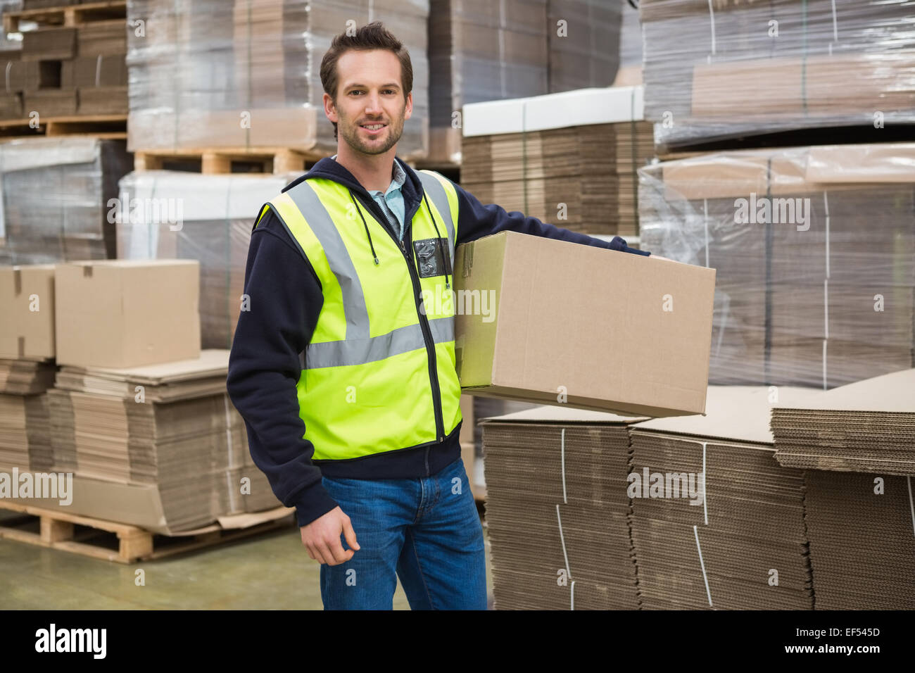 Worker carrying box in warehouse Stock Photo - Alamy