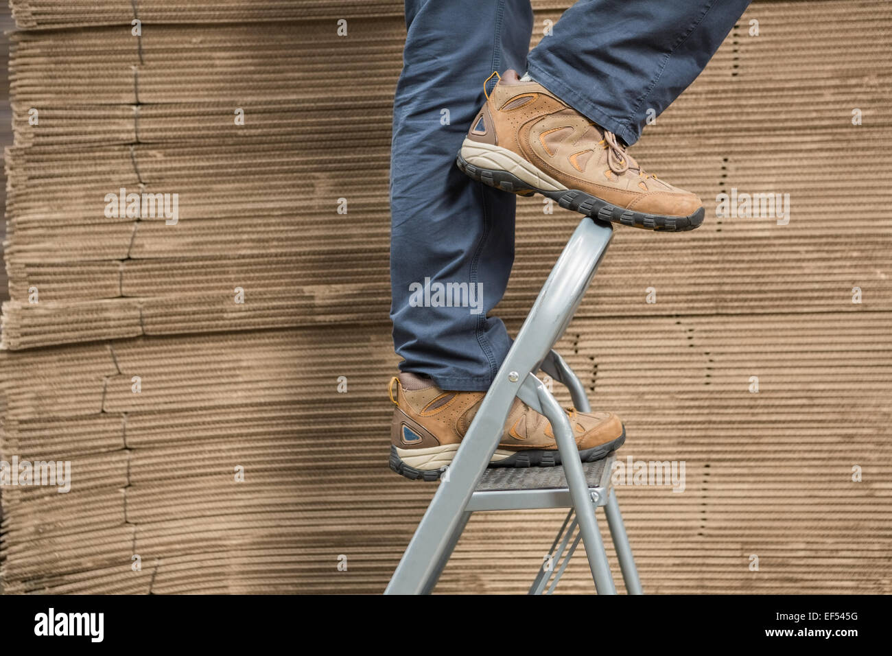 Worker on ladder in warehouse Stock Photo - Alamy