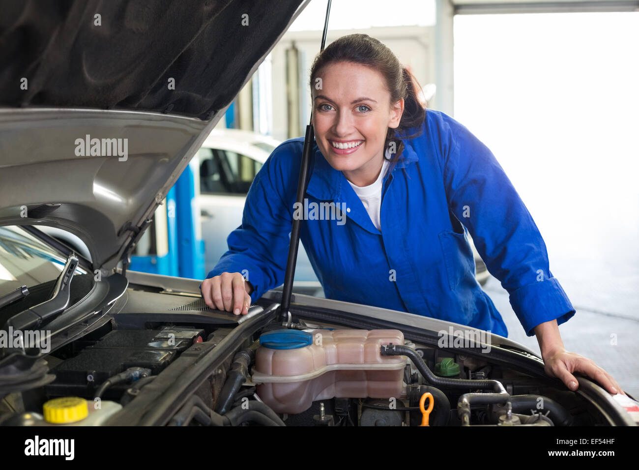 Mechanic smiling at the camera fixing engine Stock Photo - Alamy