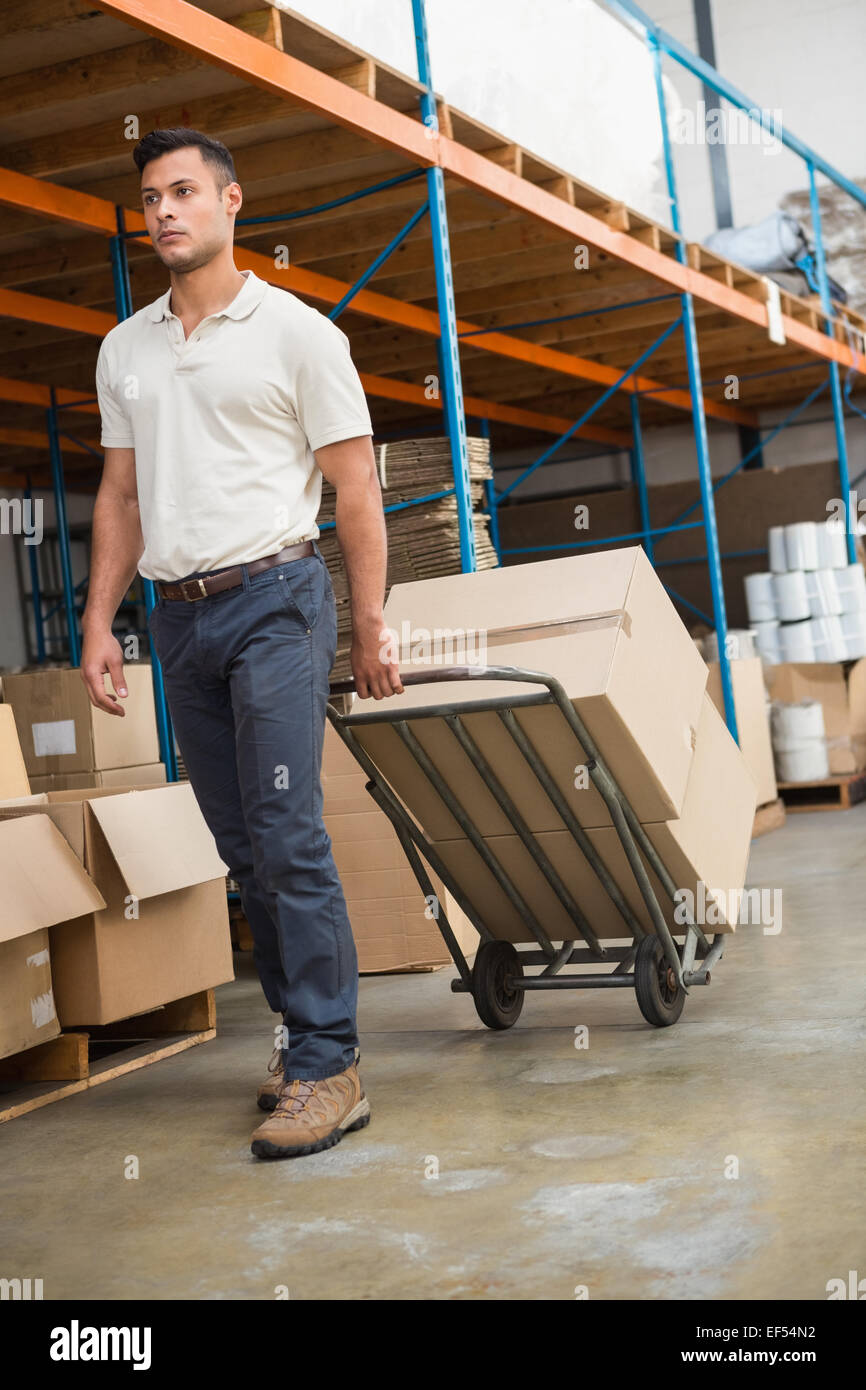 Warehouse worker moving boxes on trolley Stock Photo - Alamy