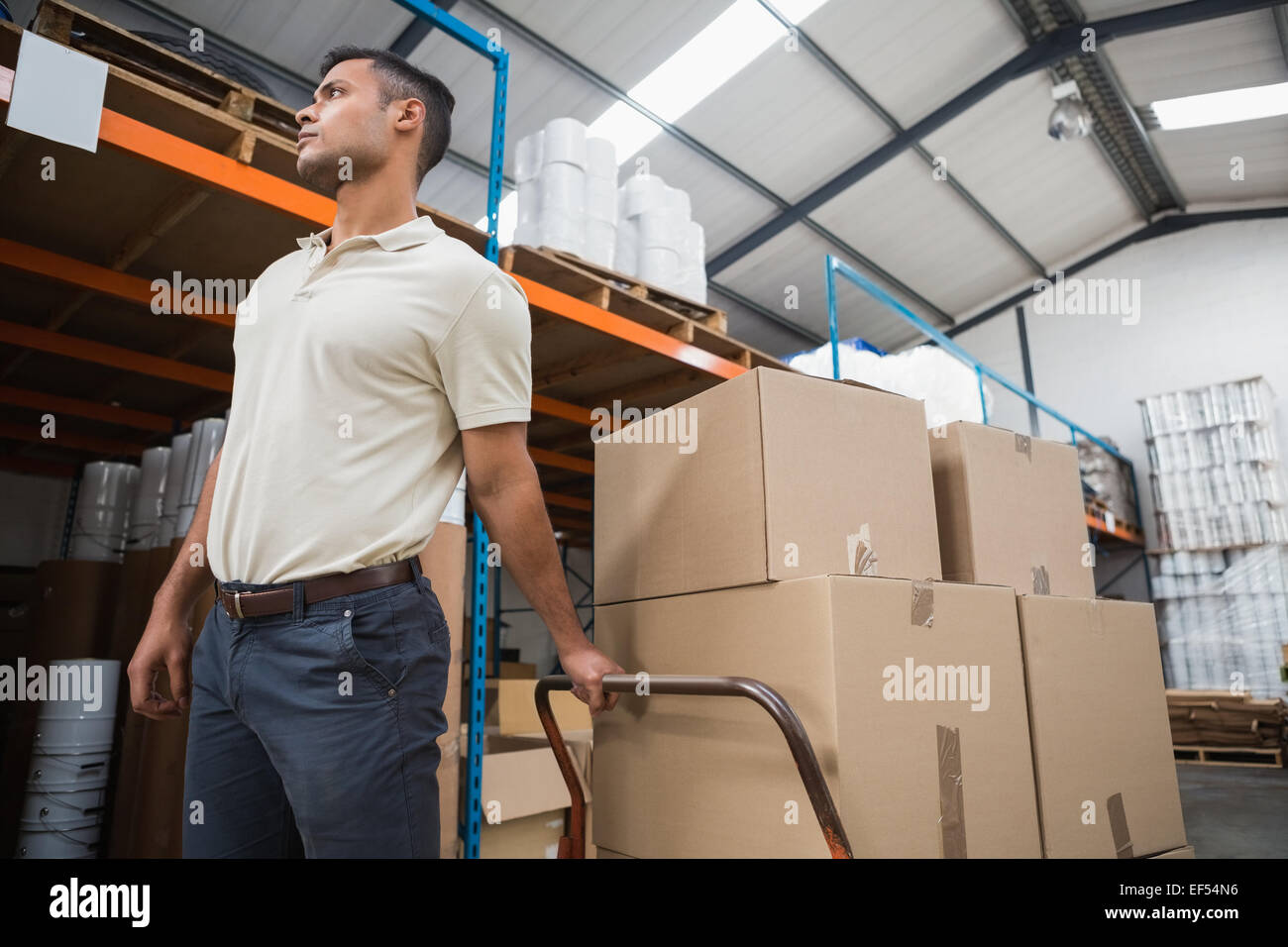 Worker pushing trolley with boxes Stock Photo - Alamy