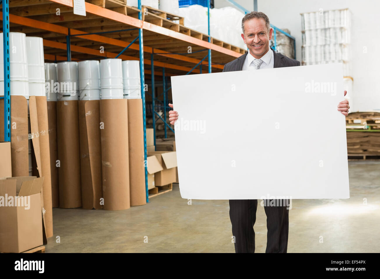 Smiling warehouse manager holding large white poster Stock Photo - Alamy