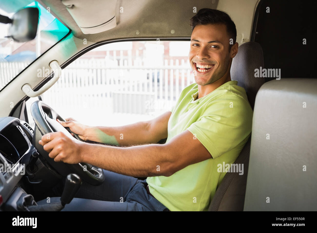 Delivery man driving his van while smiling at camera Stock Photo - Alamy