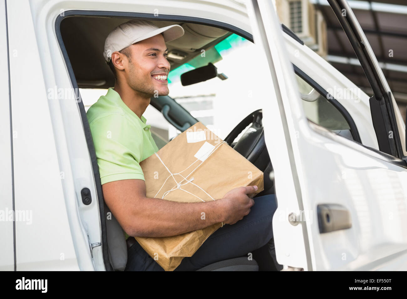 Smiling delivery driver in his van holding parcel Stock Photo - Alamy