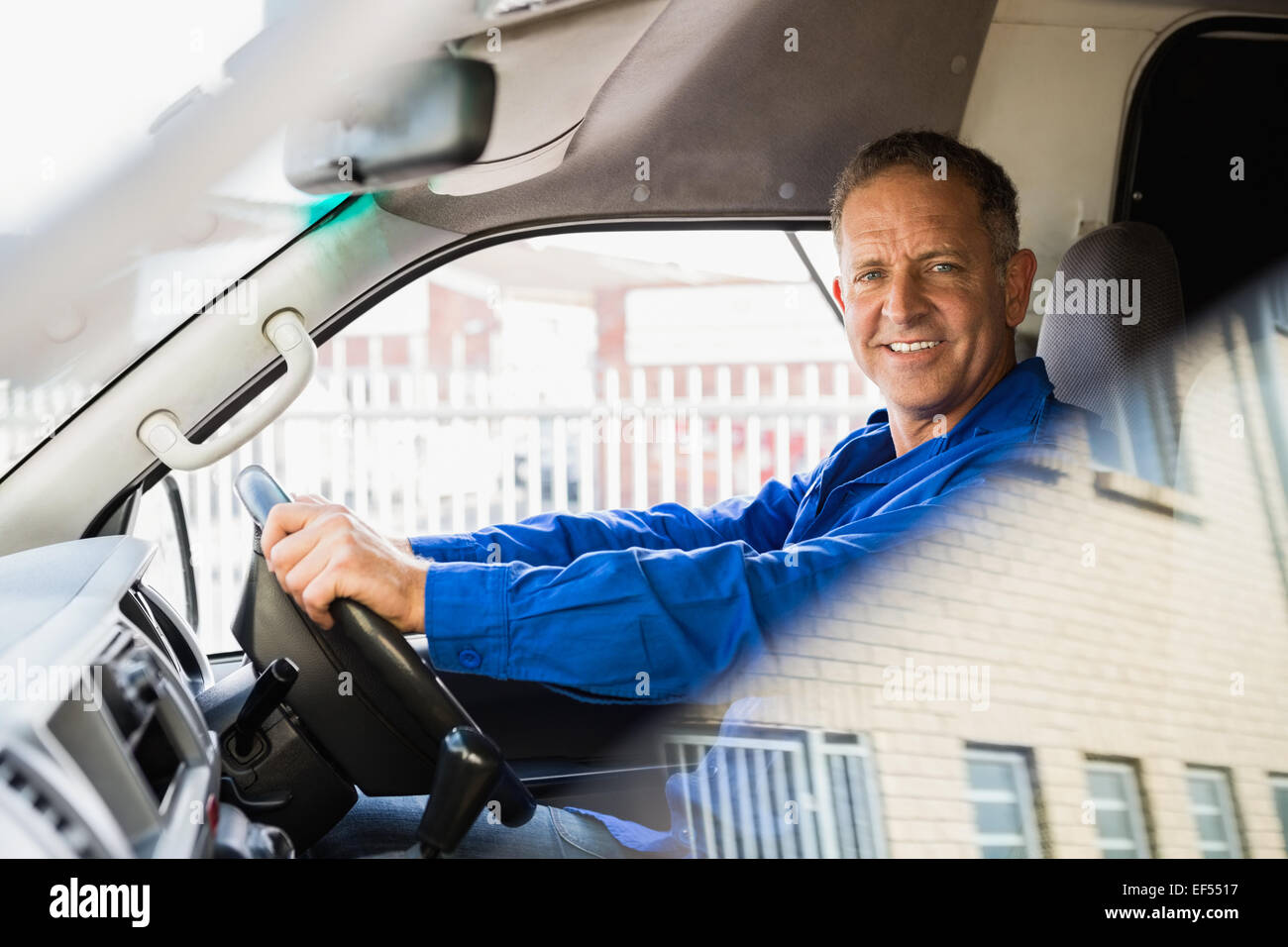 Smiling delivery man driving his van Stock Photo - Alamy