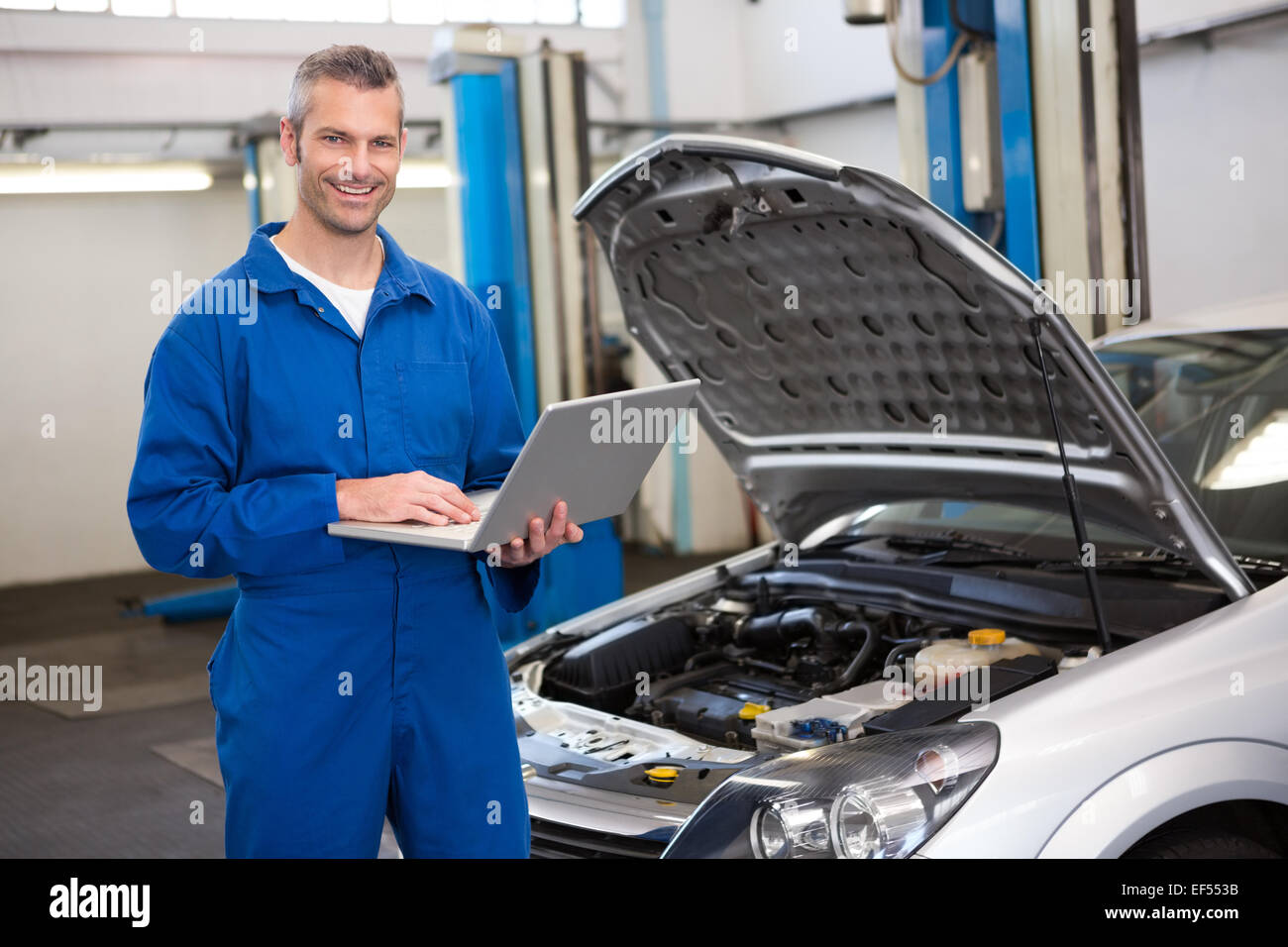 Smiling mechanic using his laptop Stock Photo - Alamy