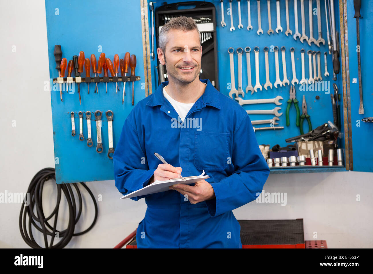 Mechanic writing on clipboard Stock Photo - Alamy