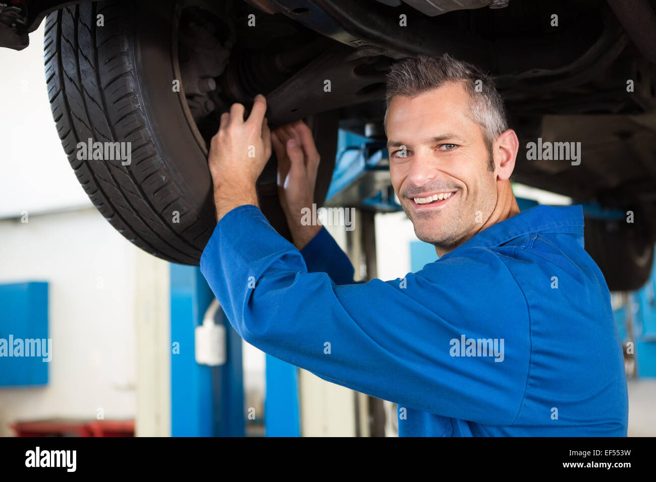 Smiling mechanic adjusting the tire Stock Photo - Alamy
