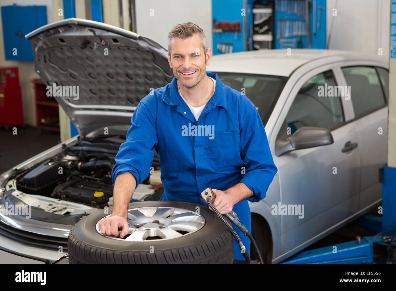 Smiling mechanic inflating the tire Stock Photo - Alamy
