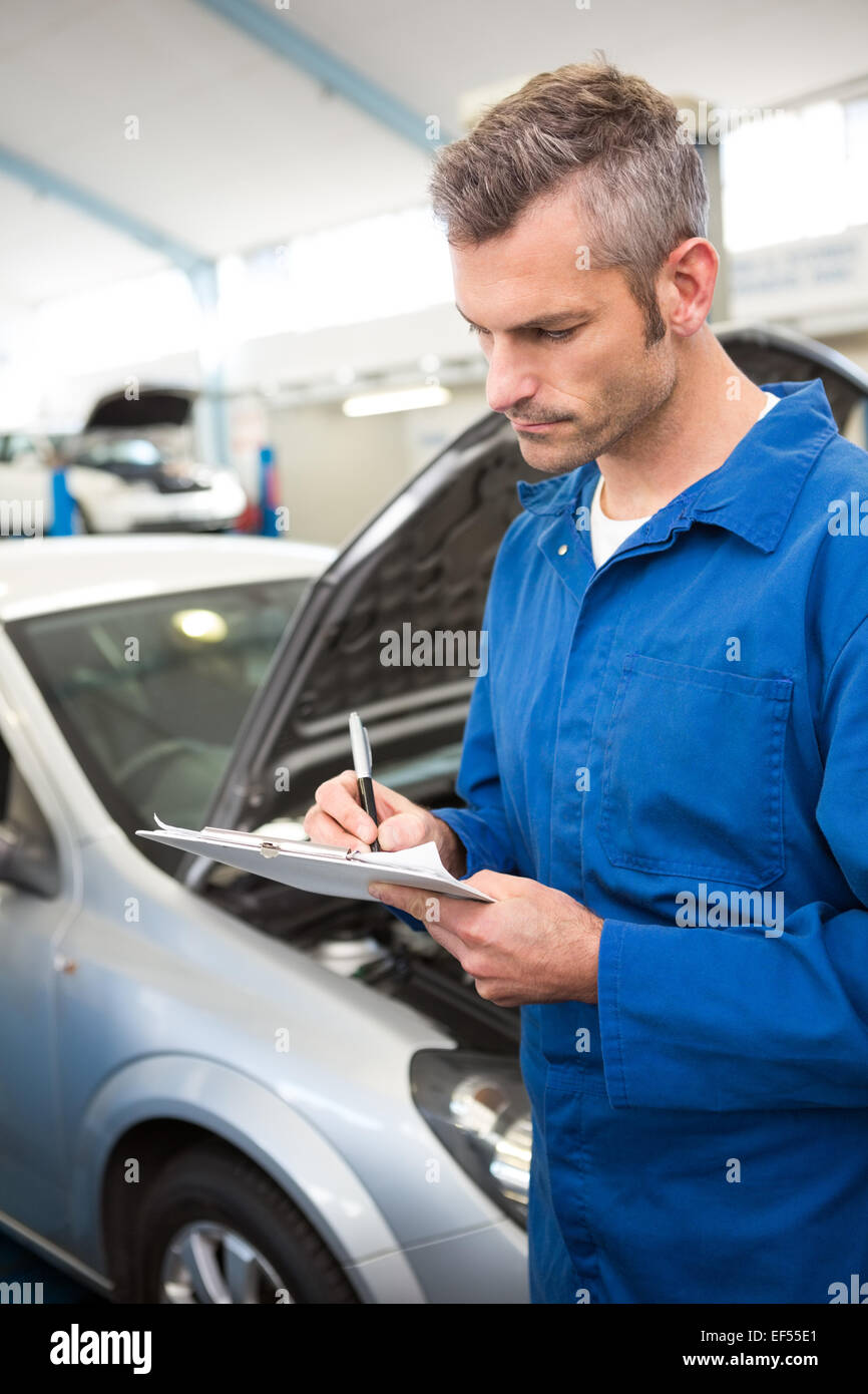 Mechanic writing on a clipboard Stock Photo - Alamy
