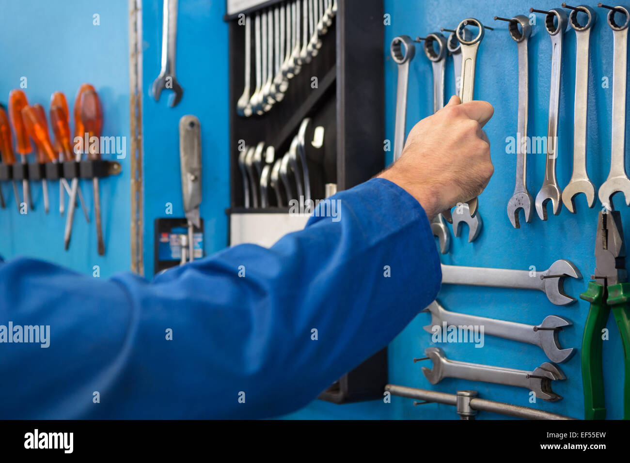 Mechanic taking a tool from wall Stock Photo - Alamy