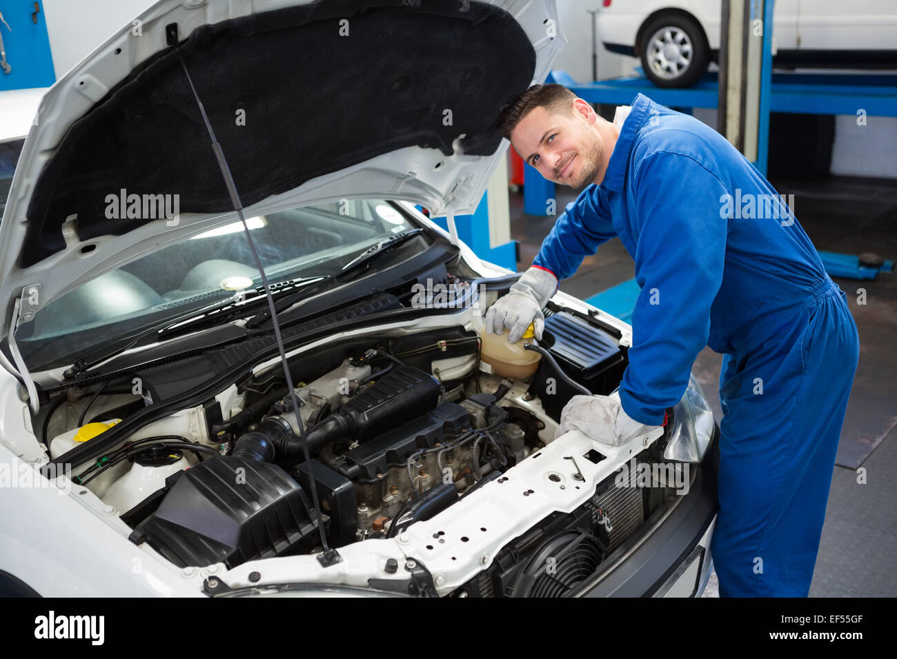 Smiling mechanic working on car Stock Photo - Alamy