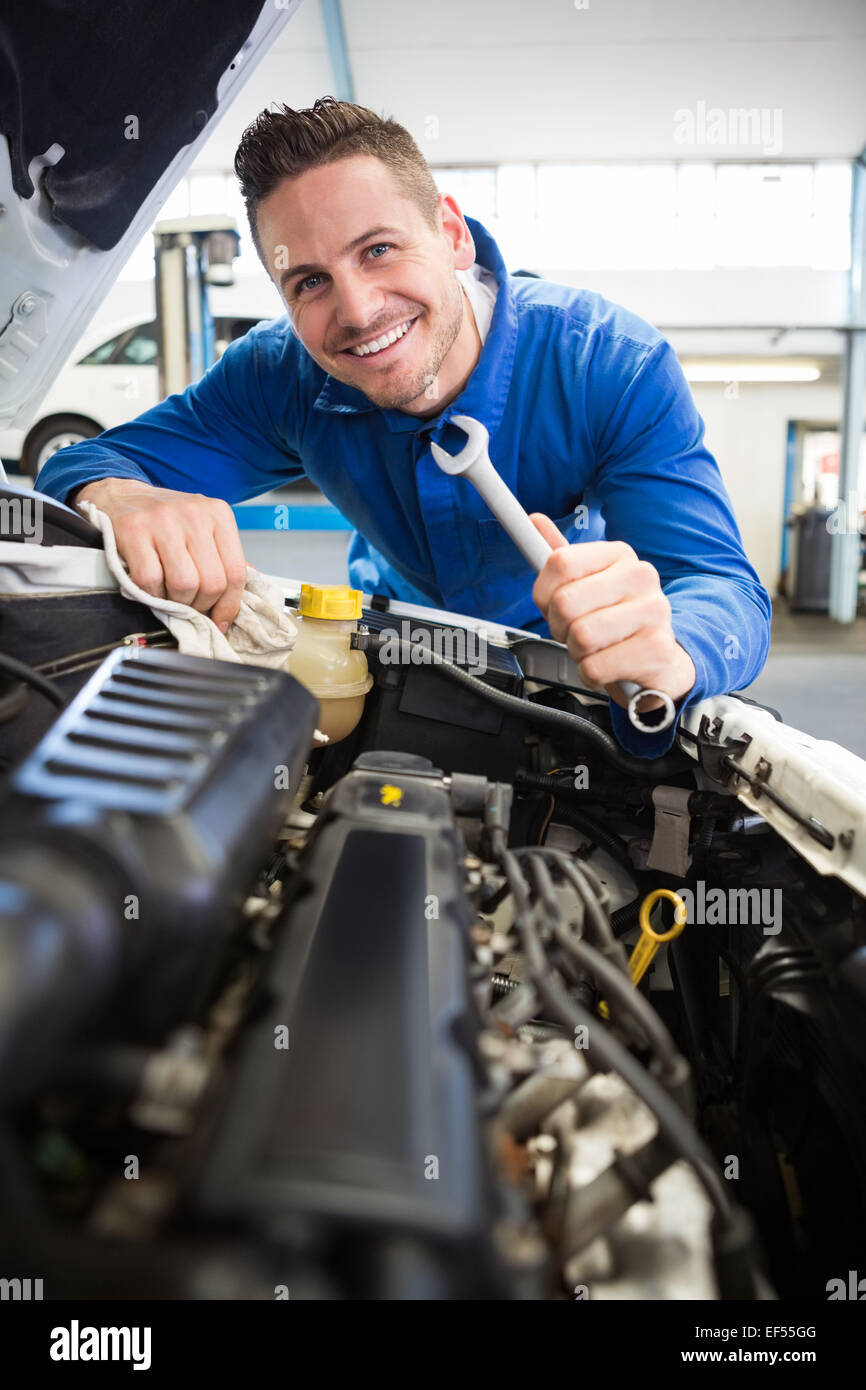 Mechanic smiling at the camera fixing engine Stock Photo - Alamy