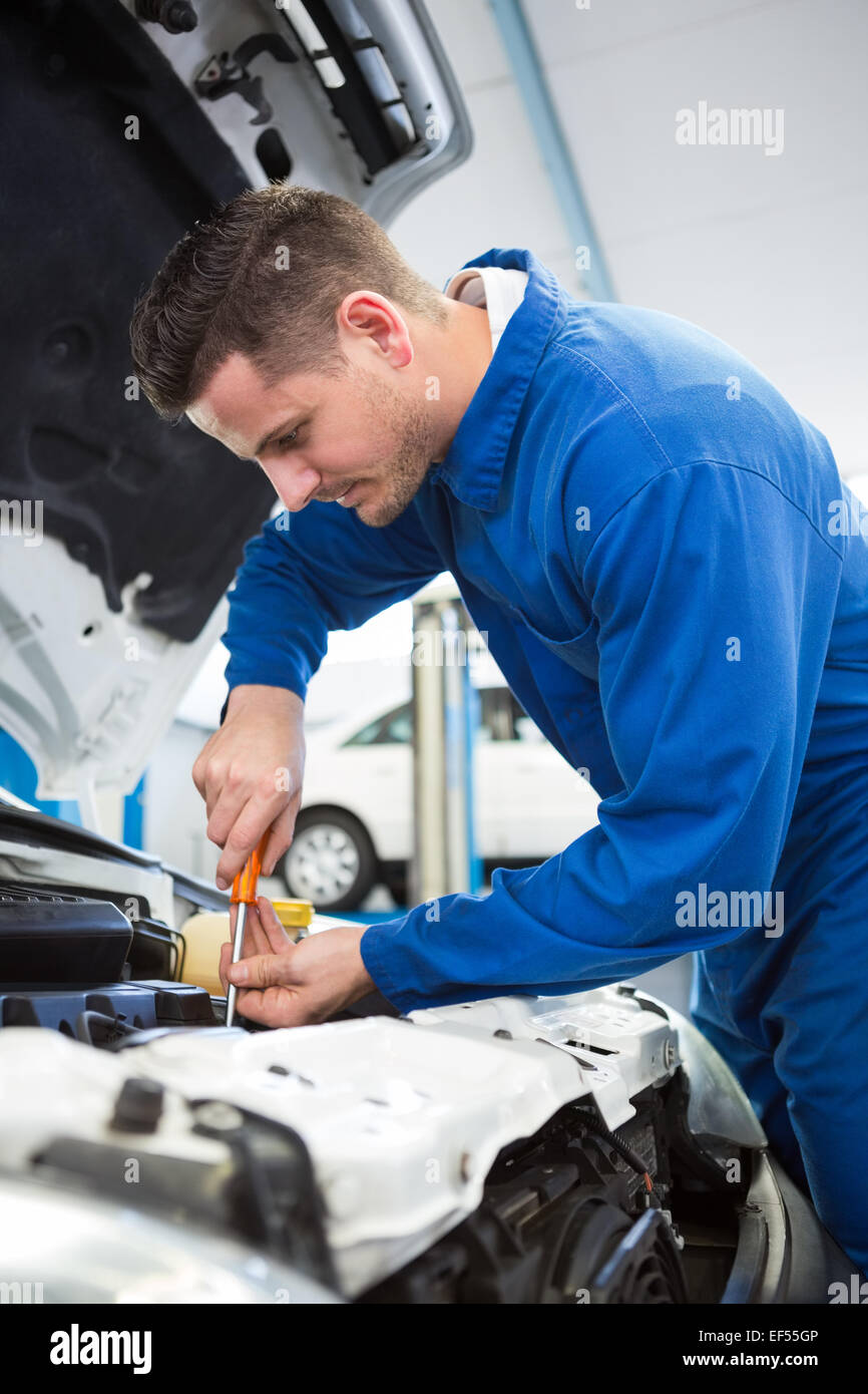 Mechanic using screwdriver on engine Stock Photo - Alamy