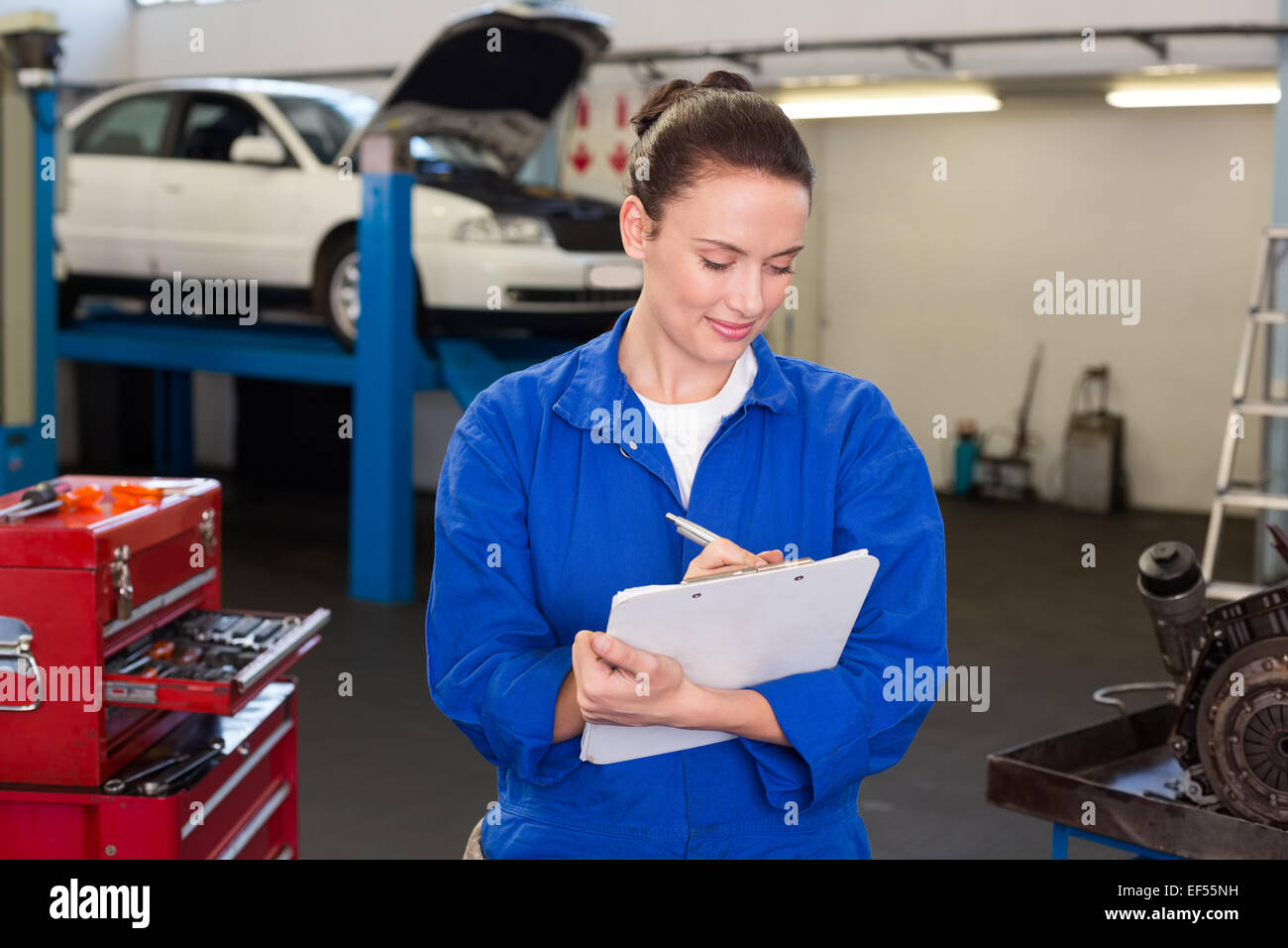 Mechanic writing on a clipboard Stock Photo - Alamy