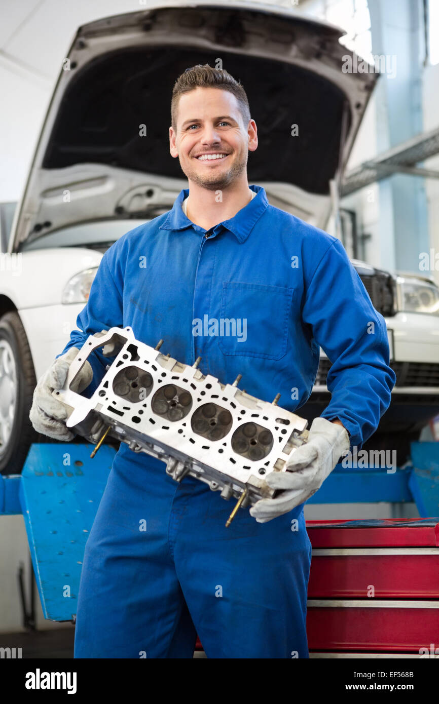 Smiling mechanic holding an engine Stock Photo - Alamy