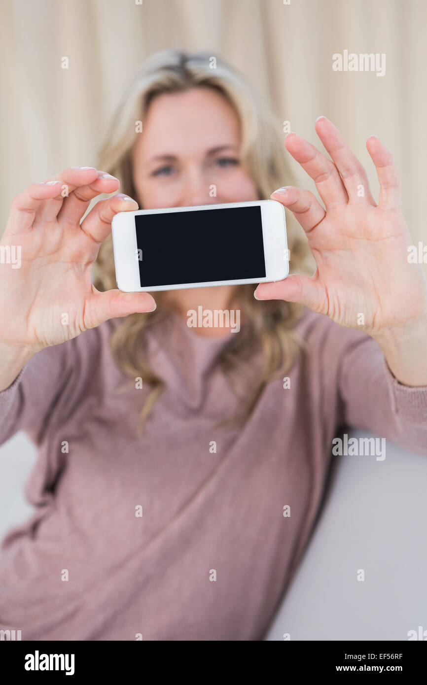 Pretty blonde showing screen of smartphone Stock Photo - Alamy