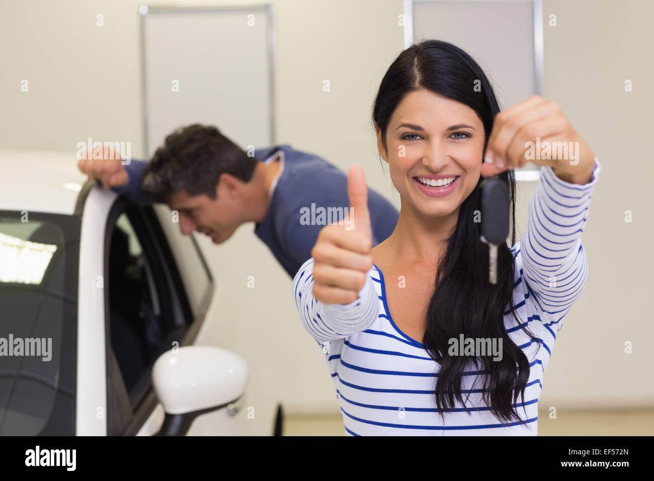 Customer holding her new car key while giving thumbs up Stock Photo - Alamy