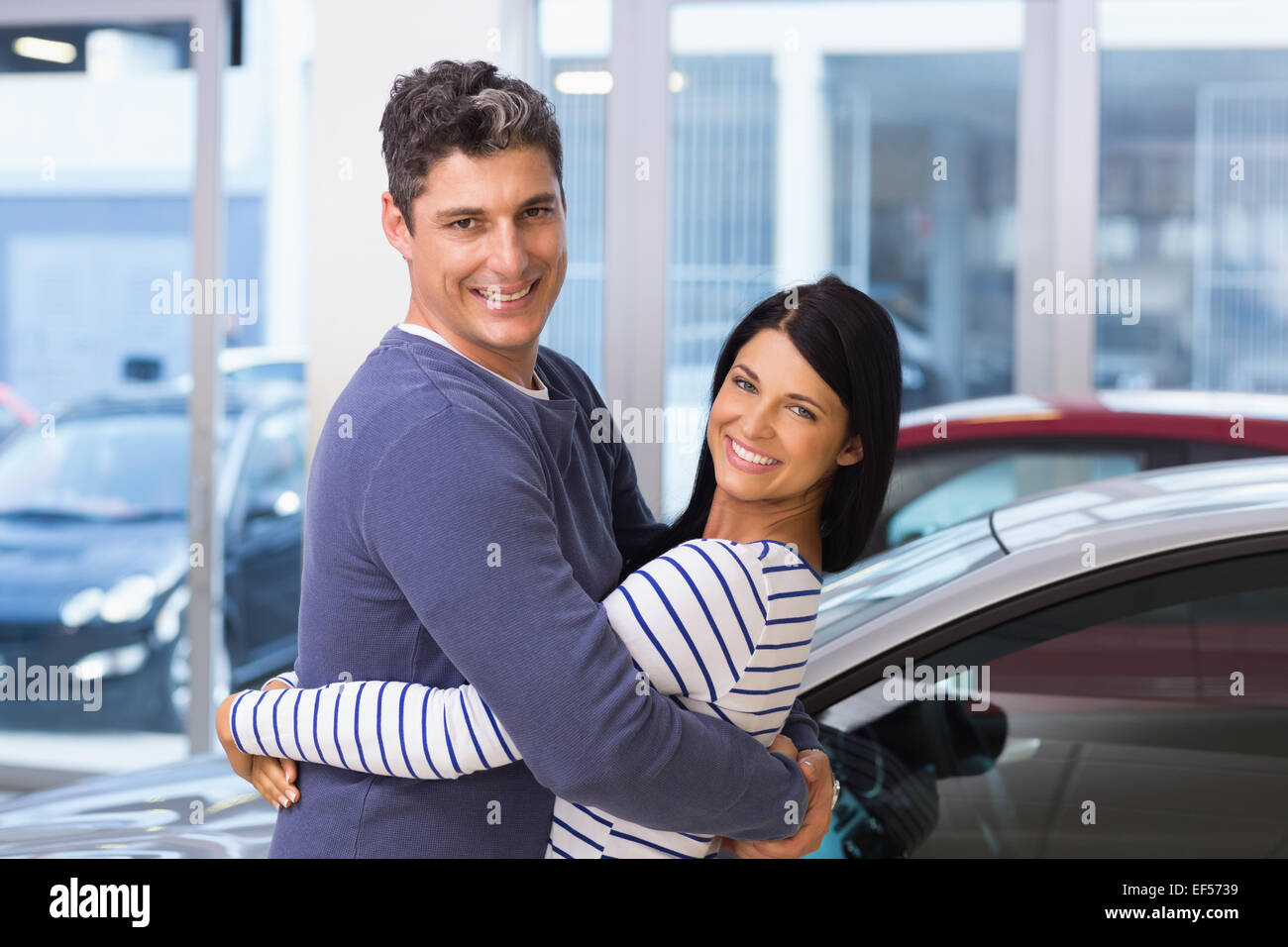 Smiling couple hugging and smiling at camera Stock Photo - Alamy