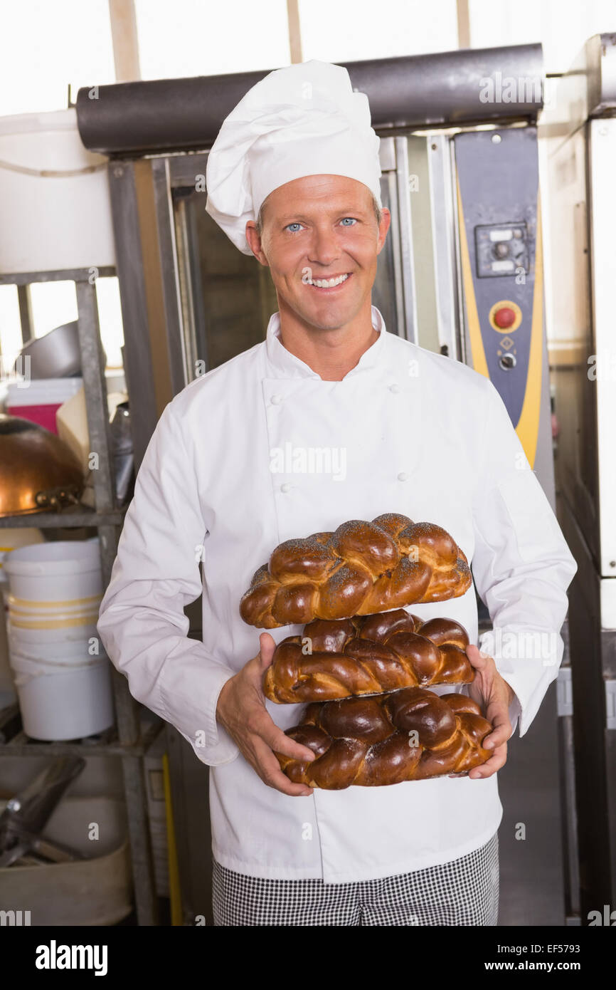 Smiling baker holding fresh loaves Stock Photo - Alamy