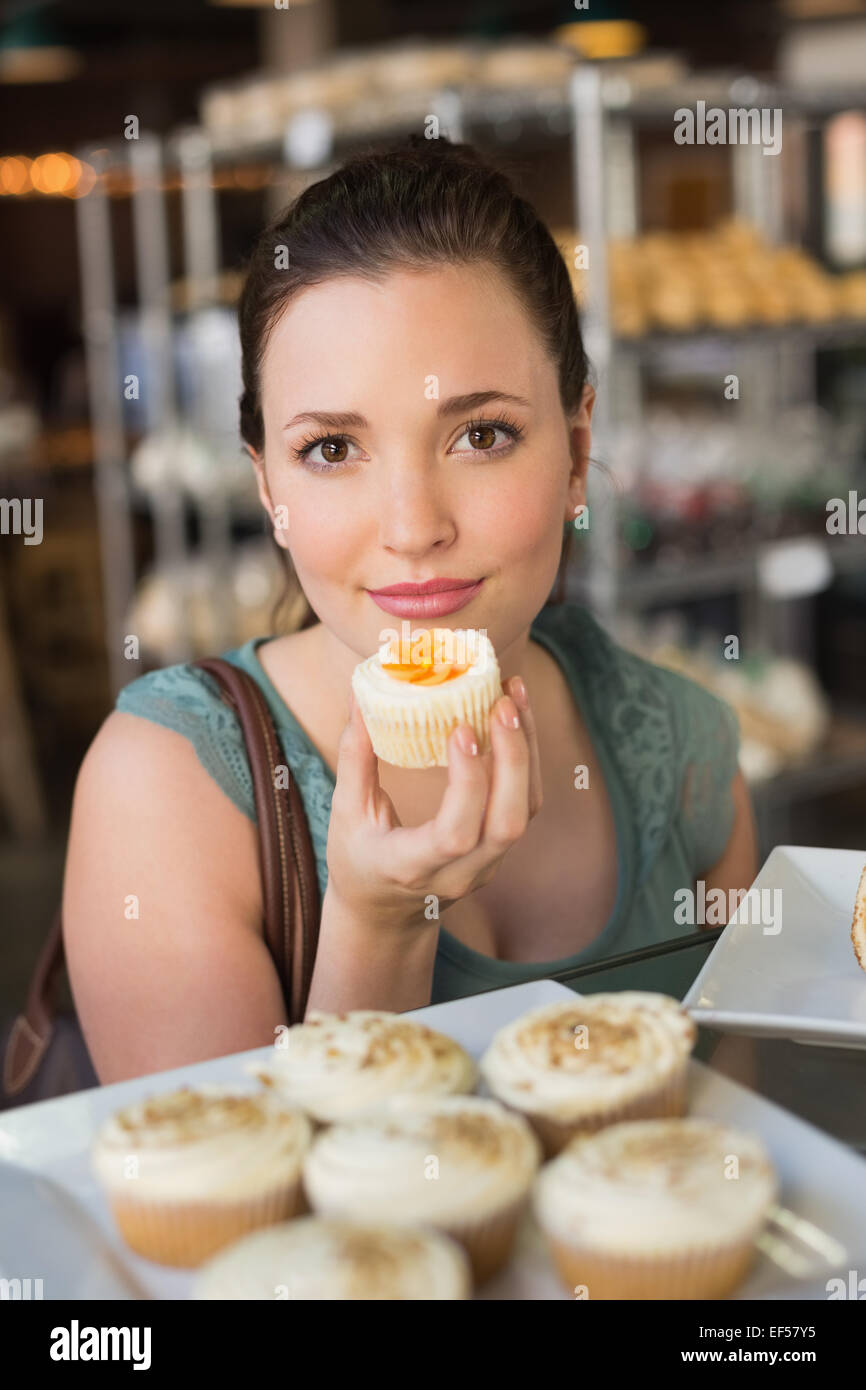 Pretty brunette smelling a cupcake Stock Photo - Alamy