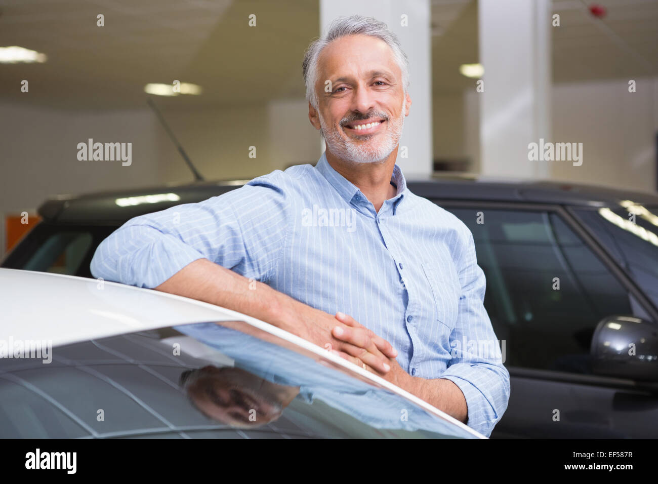 Smiling customer leaning on car Stock Photo - Alamy